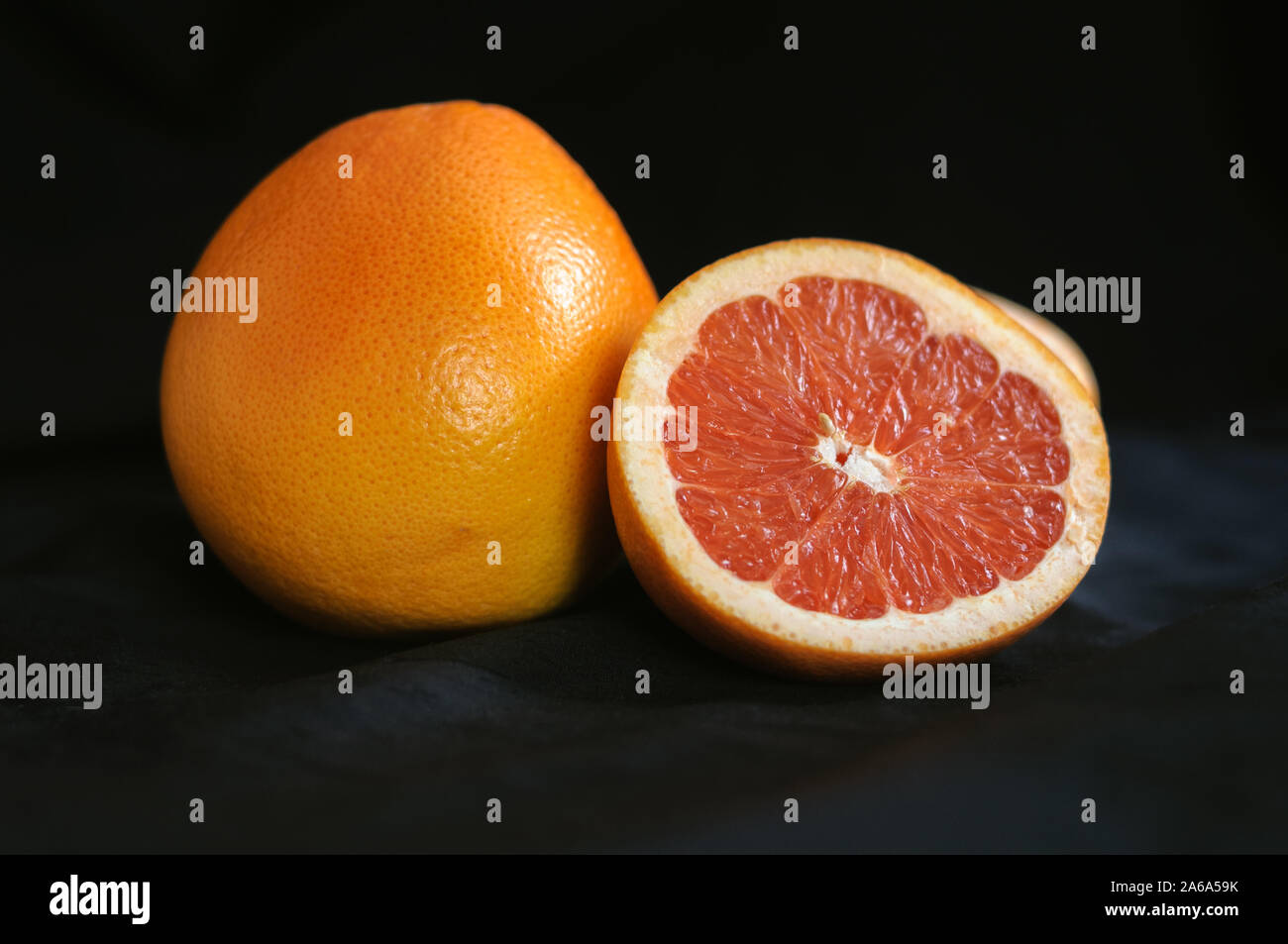 grapefruit whole and cut in half on a dark background Stock Photo - Alamy