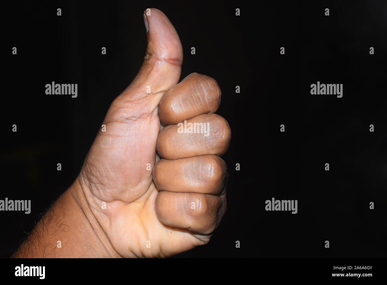 Closeup of hand showing thumbs up sign on black background with ...