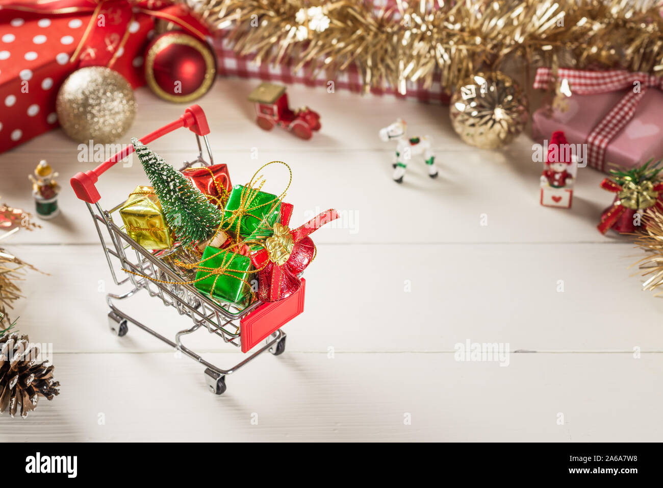 Shopping cart with christmas tree and miniature gift boxes on white ...