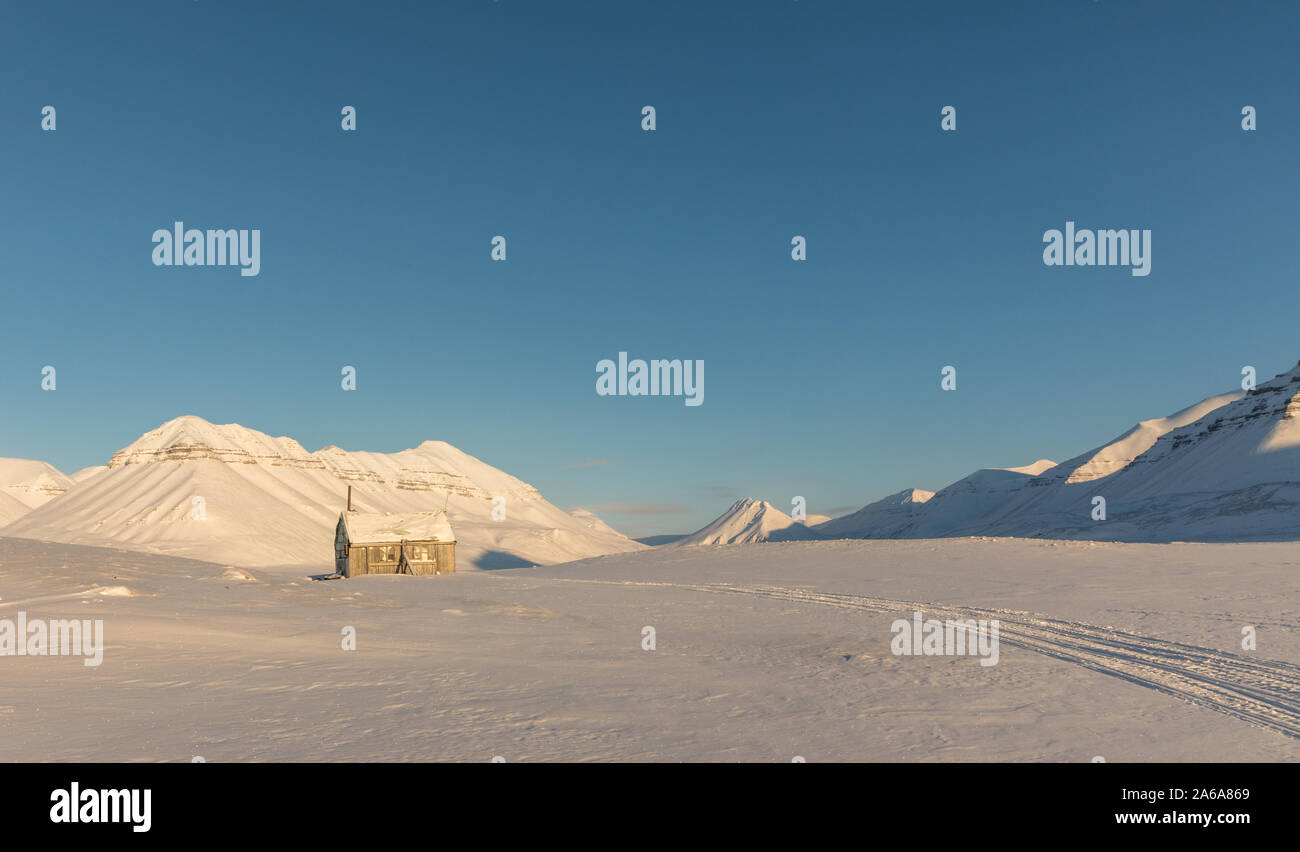 Small cabin in the arctic winter landscape with snow covered mountains ...