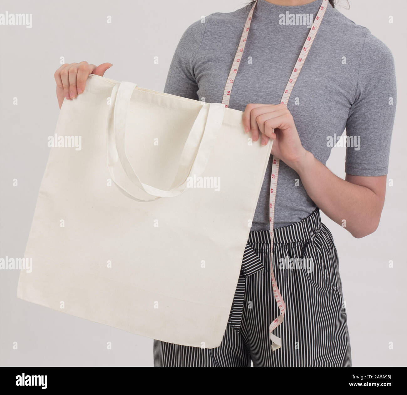 A woman with measuring tape showing a fabric bag on white background ...