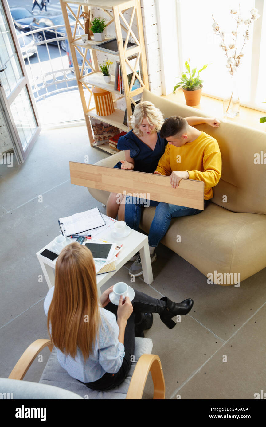 Interior designer working with young couple. Lovely family and ...