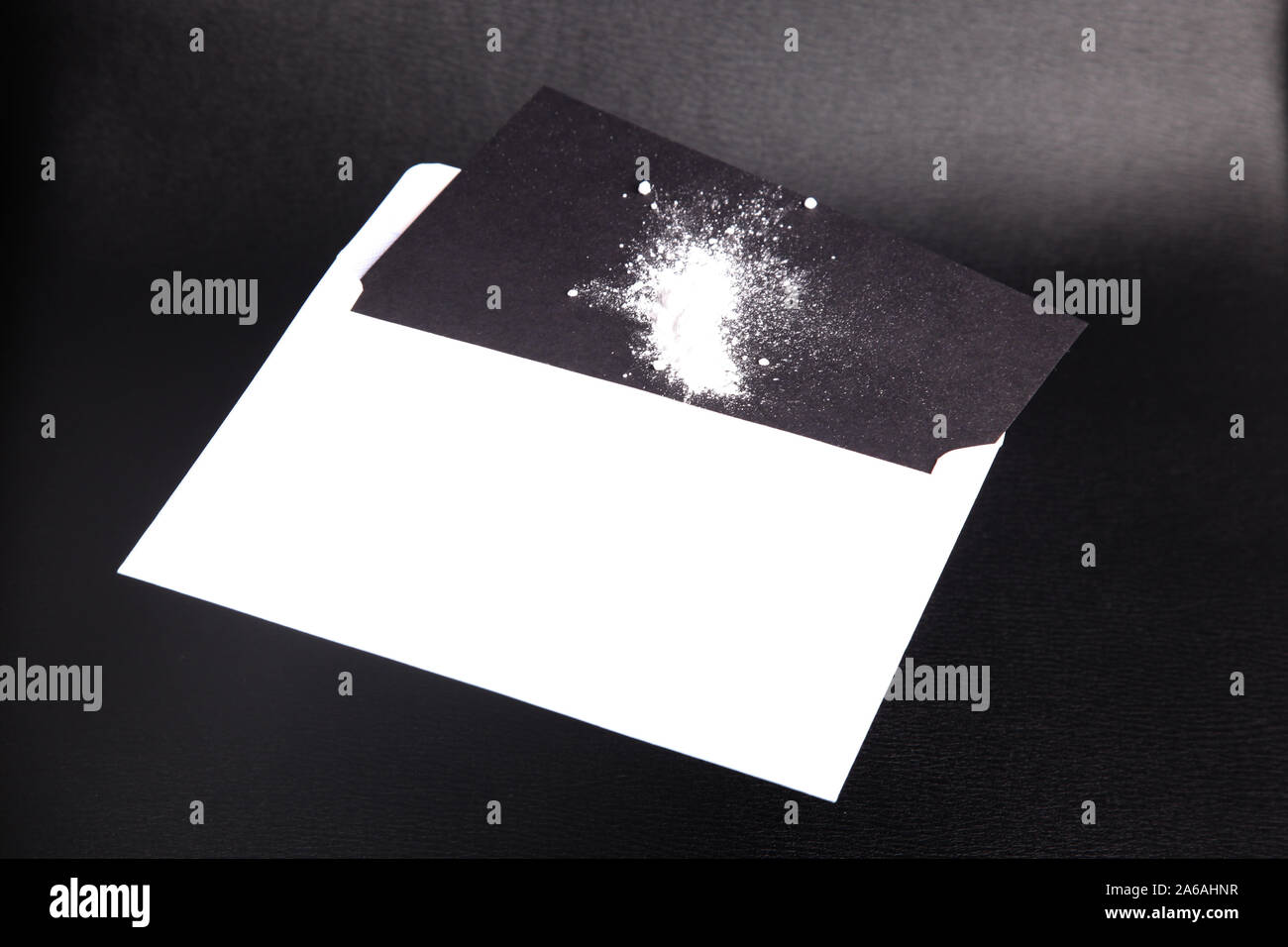 Ricin white powder being inserted in / removed from envelope on black ...