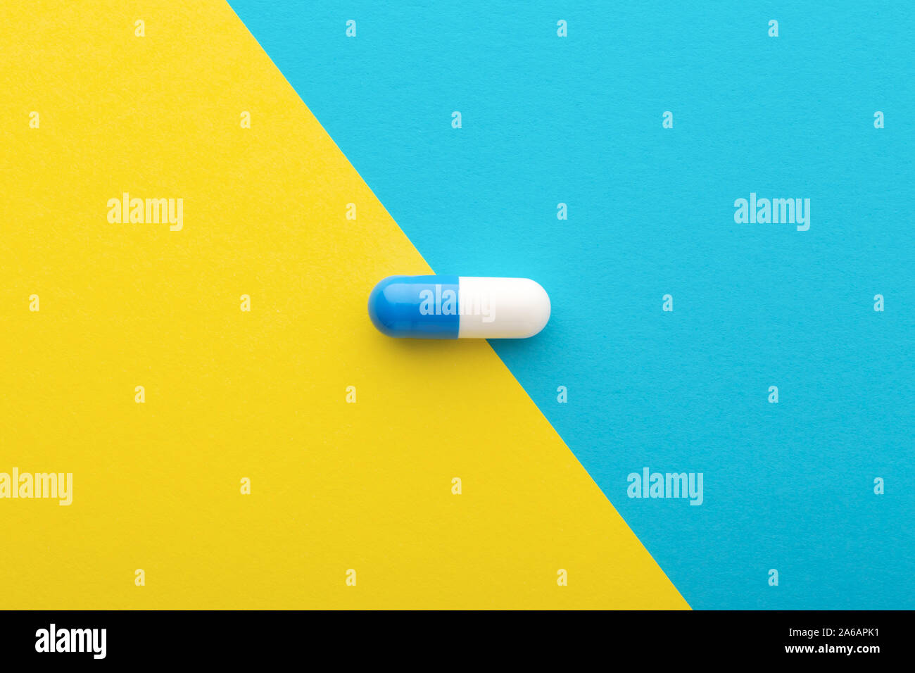 Pharmaceutical pill, blue white capsule on yellow blue background ...