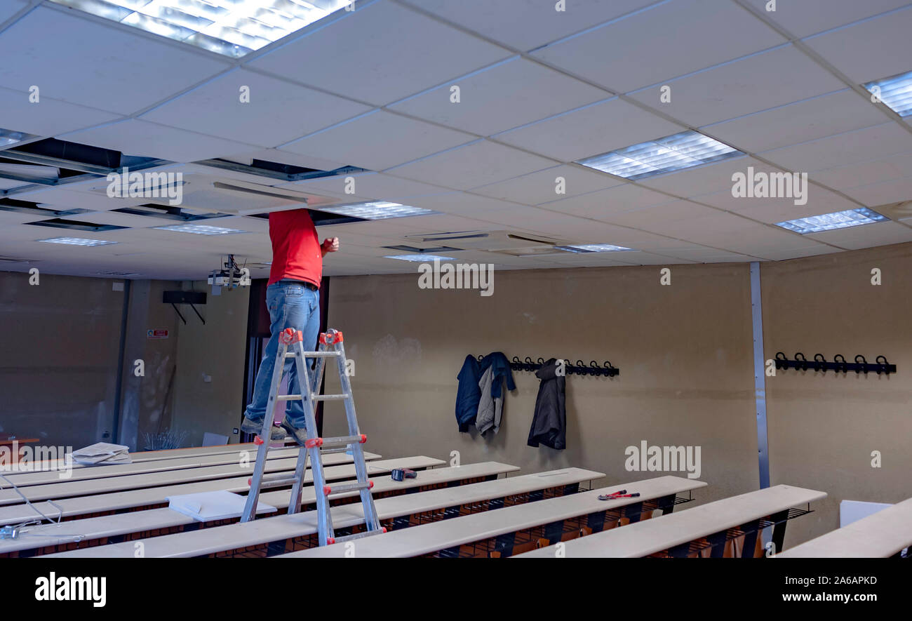 Worker repairing board ceiling with gypsum. In the classroom Stock ...