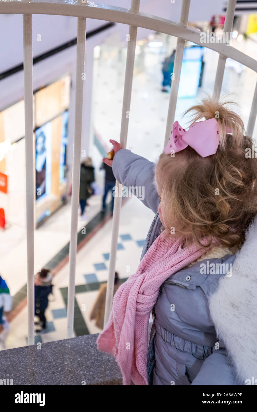 A little girl aged 2 gazes over the balcony at the Intu shopping centre ...