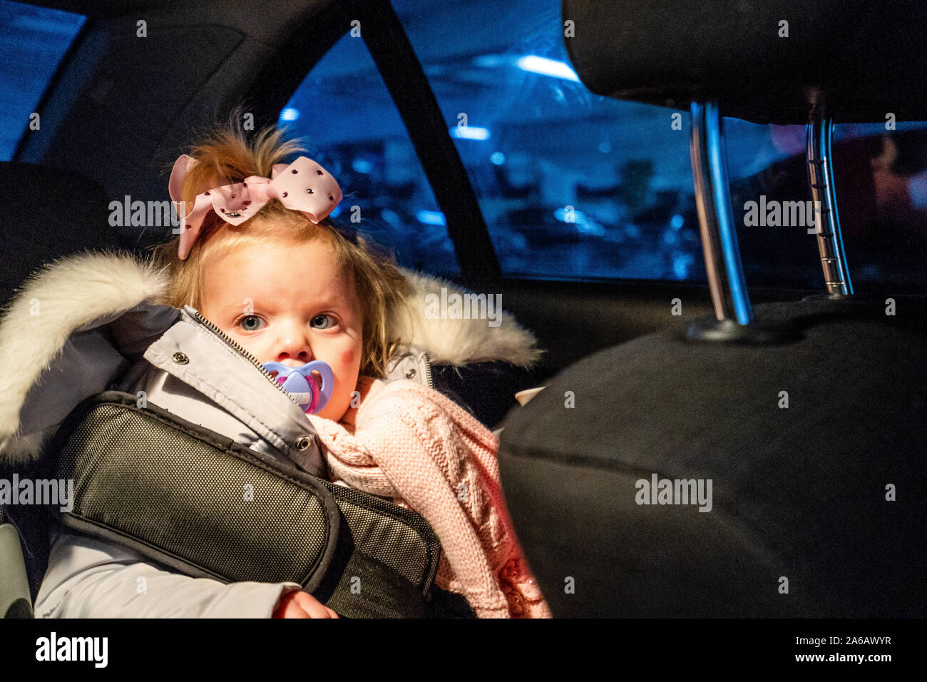 A pretty little girl with rosey cheeks sits inside a car in her car ...
