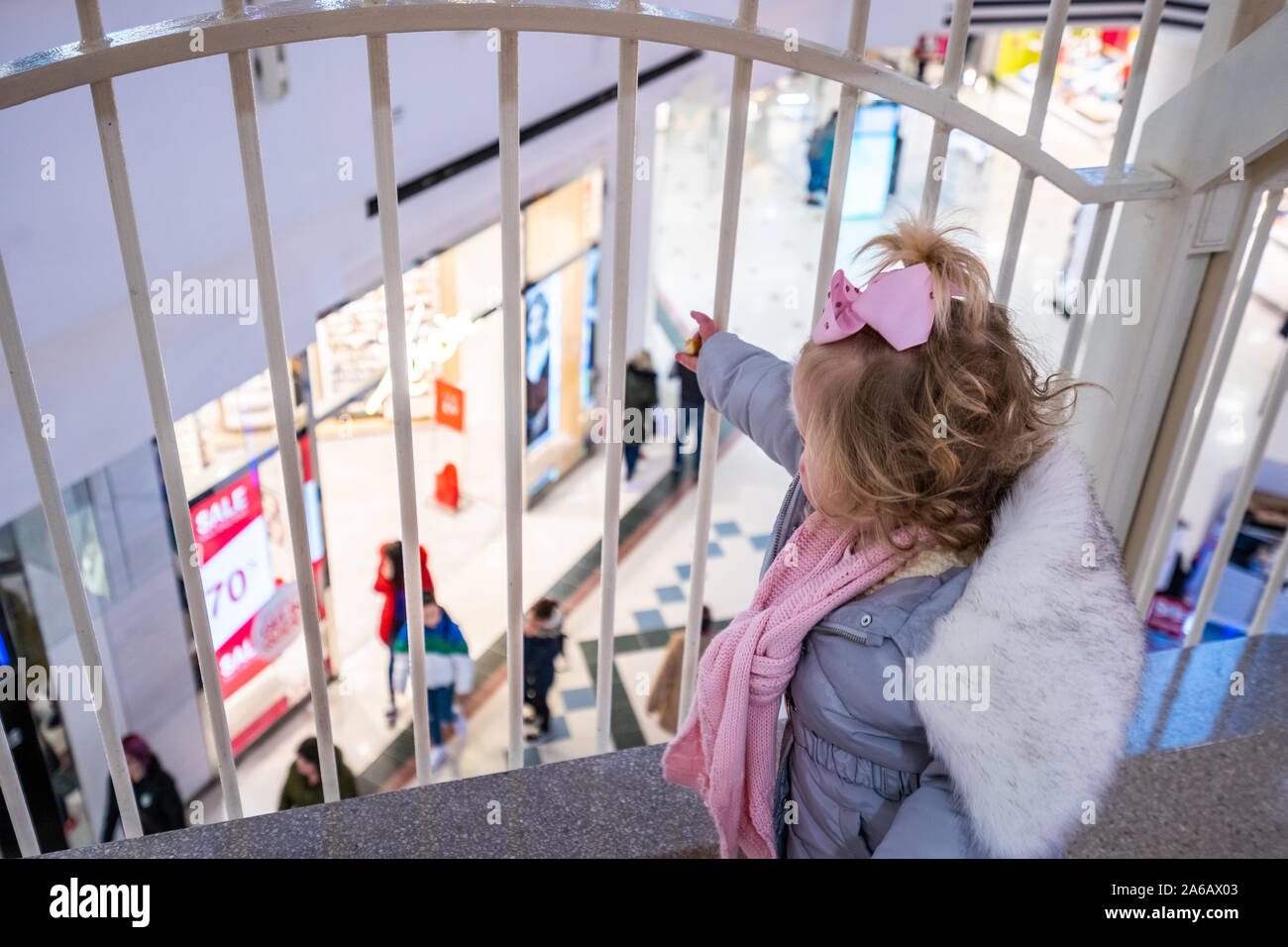 A little girl aged 2 gazes over the balcony at the Intu shopping centre ...