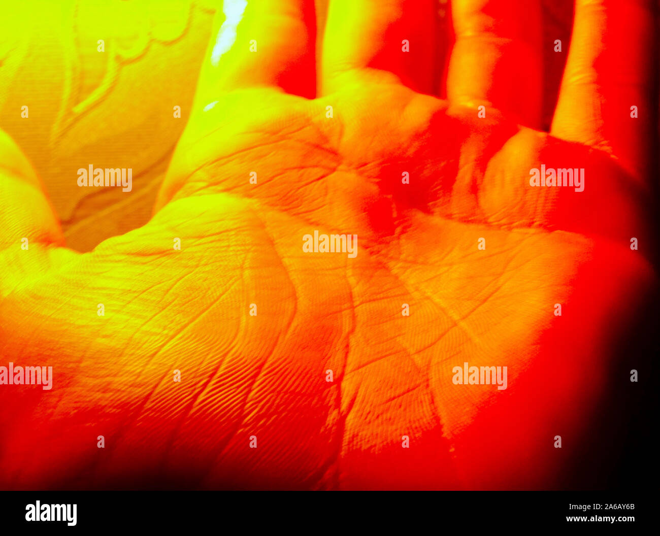 The slightly blurred outline of a human hand illuminated by a Desk lamp ...