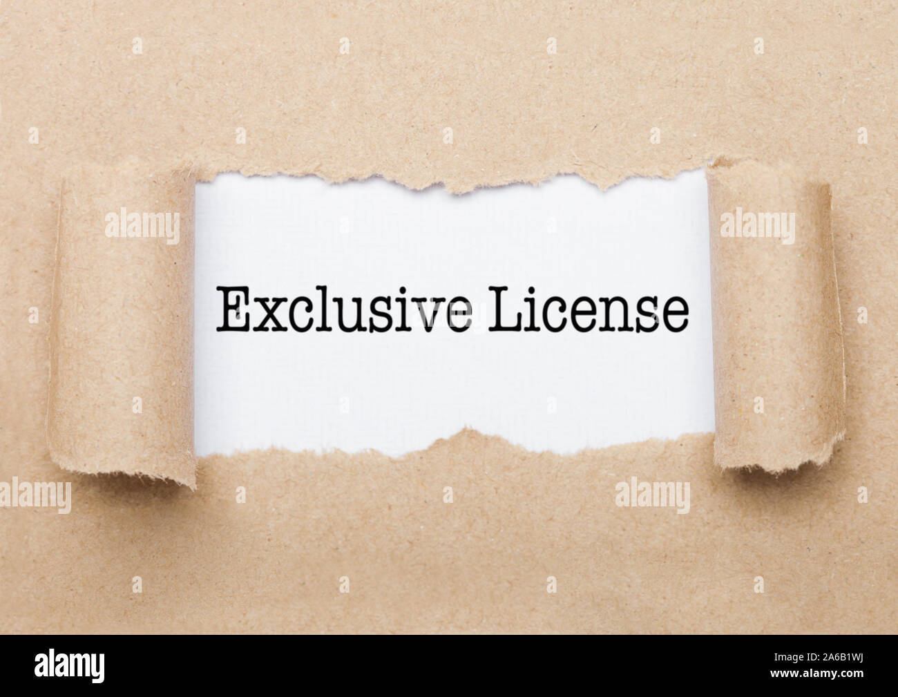 Exclusive License concept text appearing behind torn brown paper ...