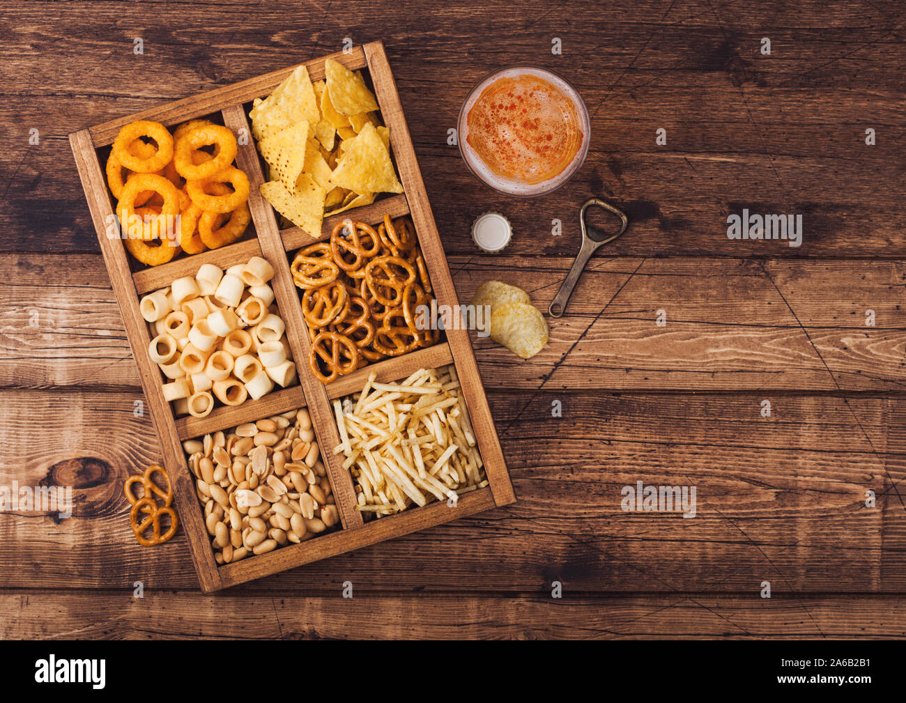 Glass of craft lager beer and opener with box of snacks on wood ...