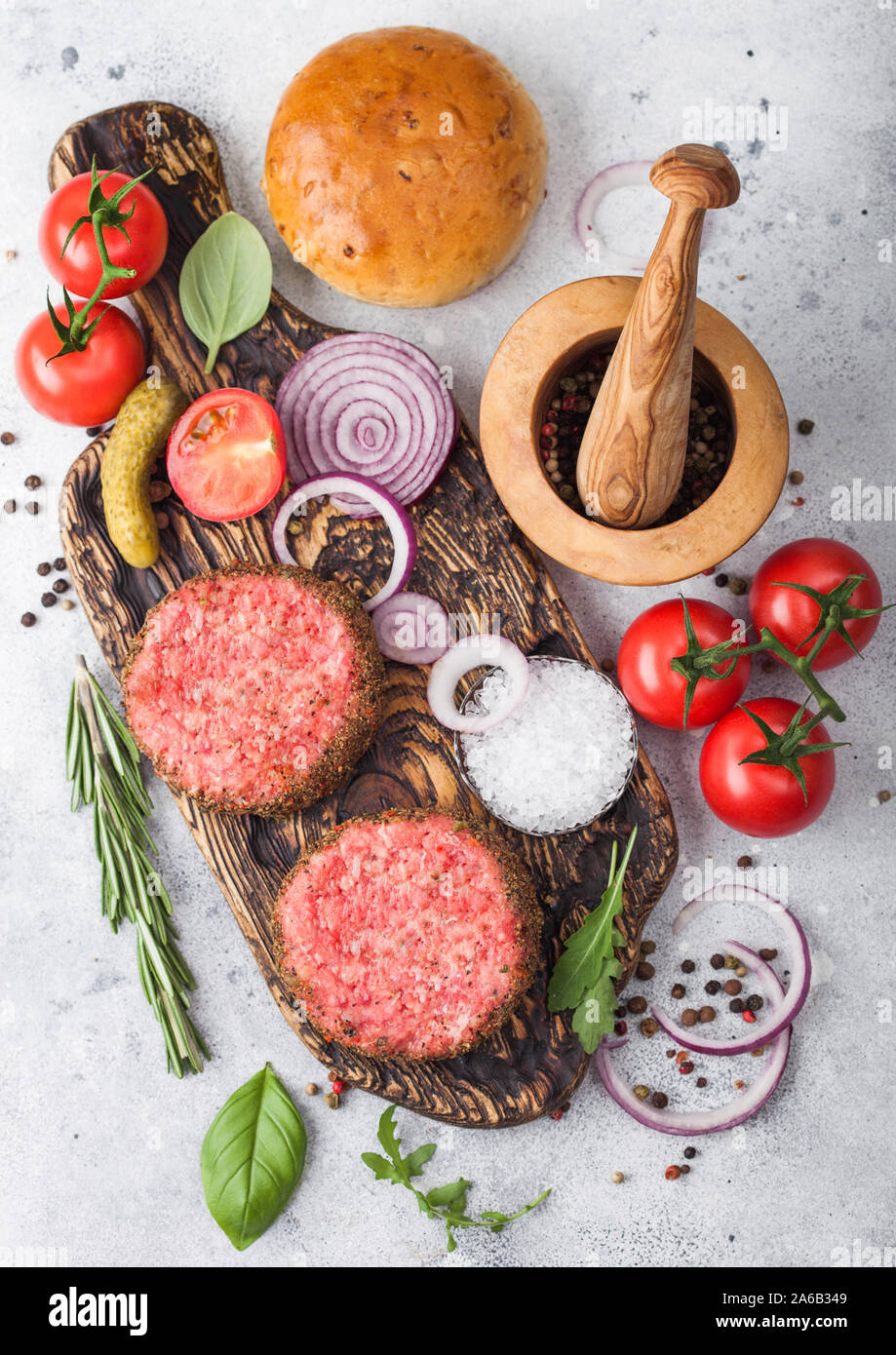 Fresh raw minced pepper beef burgers on vintage chopping board with ...