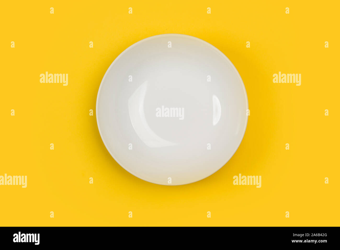 A deep white ceramic plate on a yellow background Stock Photo - Alamy