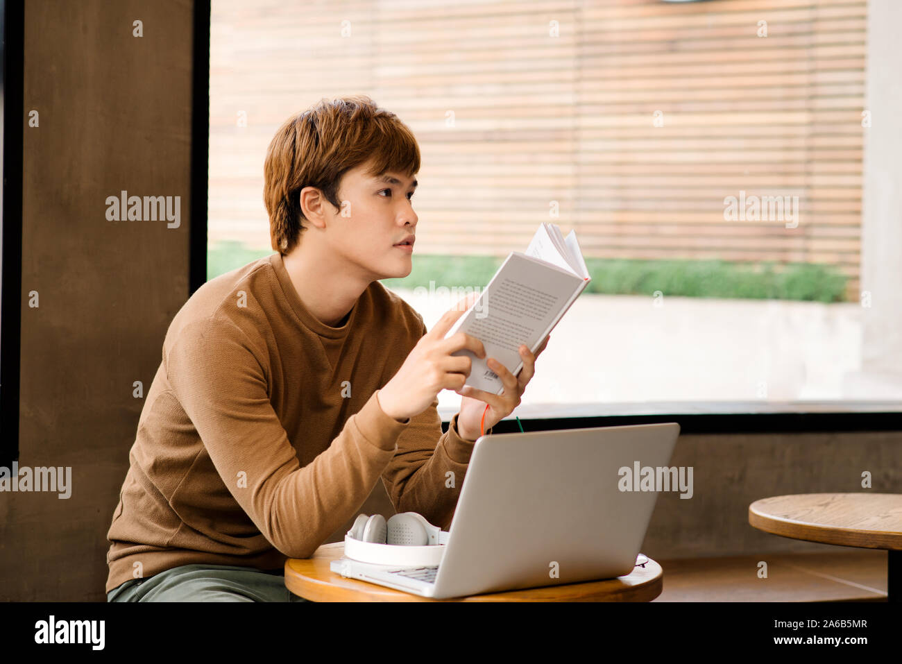 Asian man reading book in coffee shop Stock Photo - Alamy