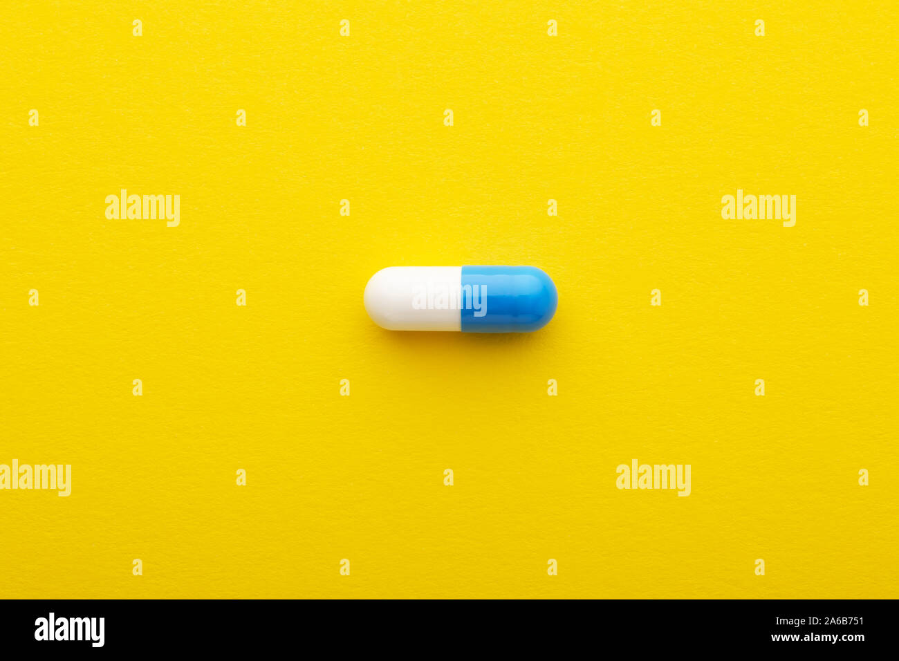 Pharmaceutical pill, blue white capsule on yellow background, flatlay ...