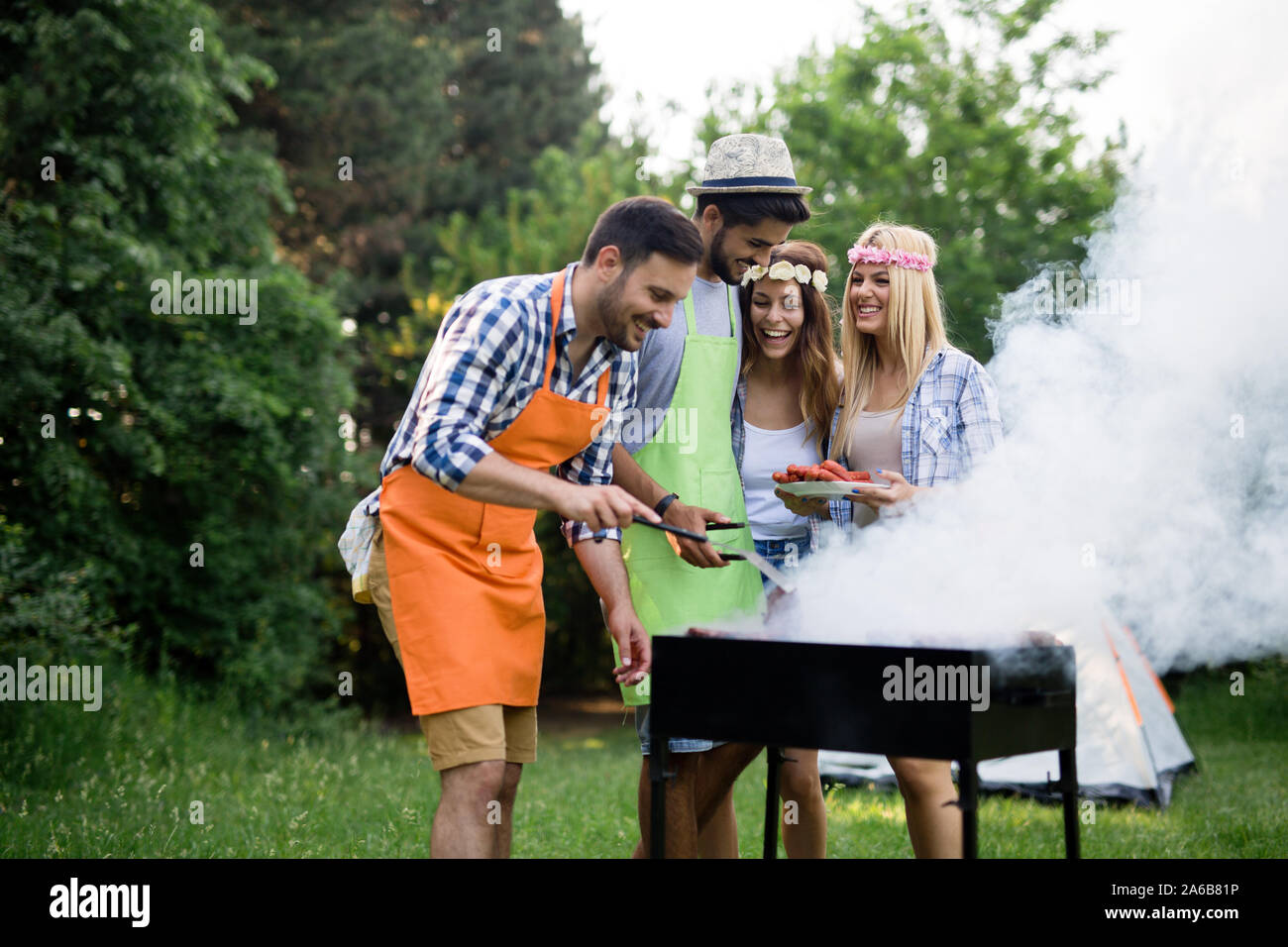 Group of friends making a barbecue together outdoors in the nature ...