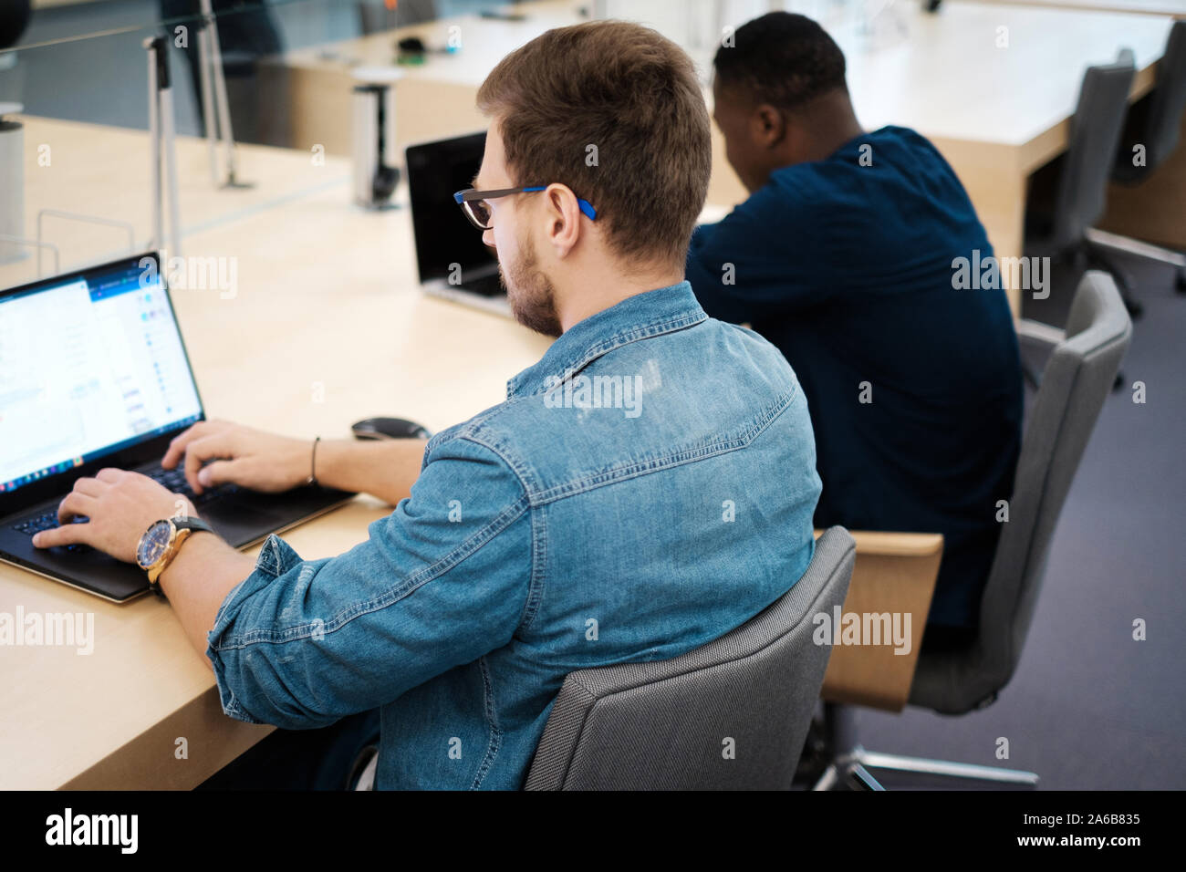 Young men working on a laptops in public library Stock Photo - Alamy