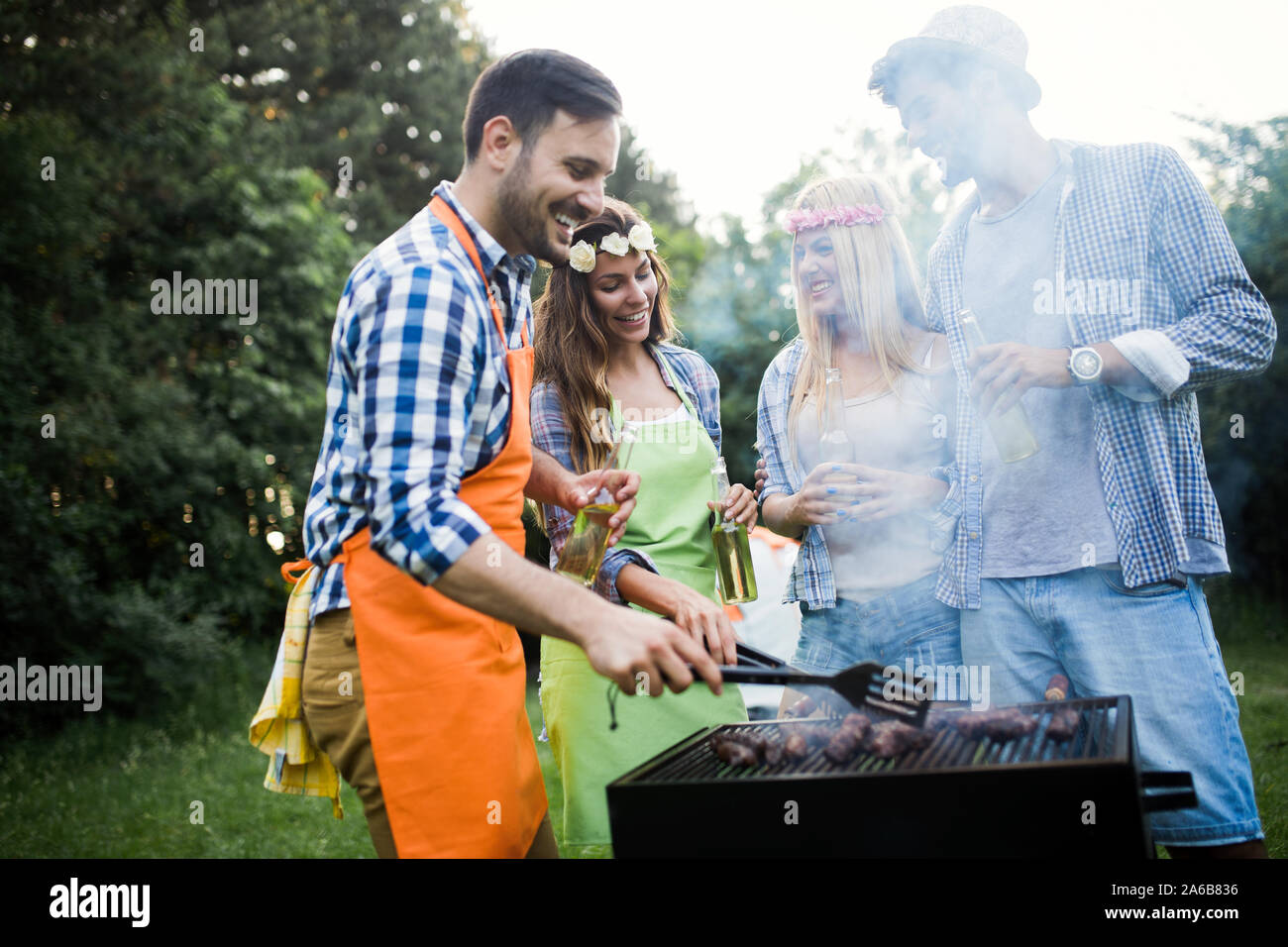 Group of happy people standing around grill, chatting, drinking and ...