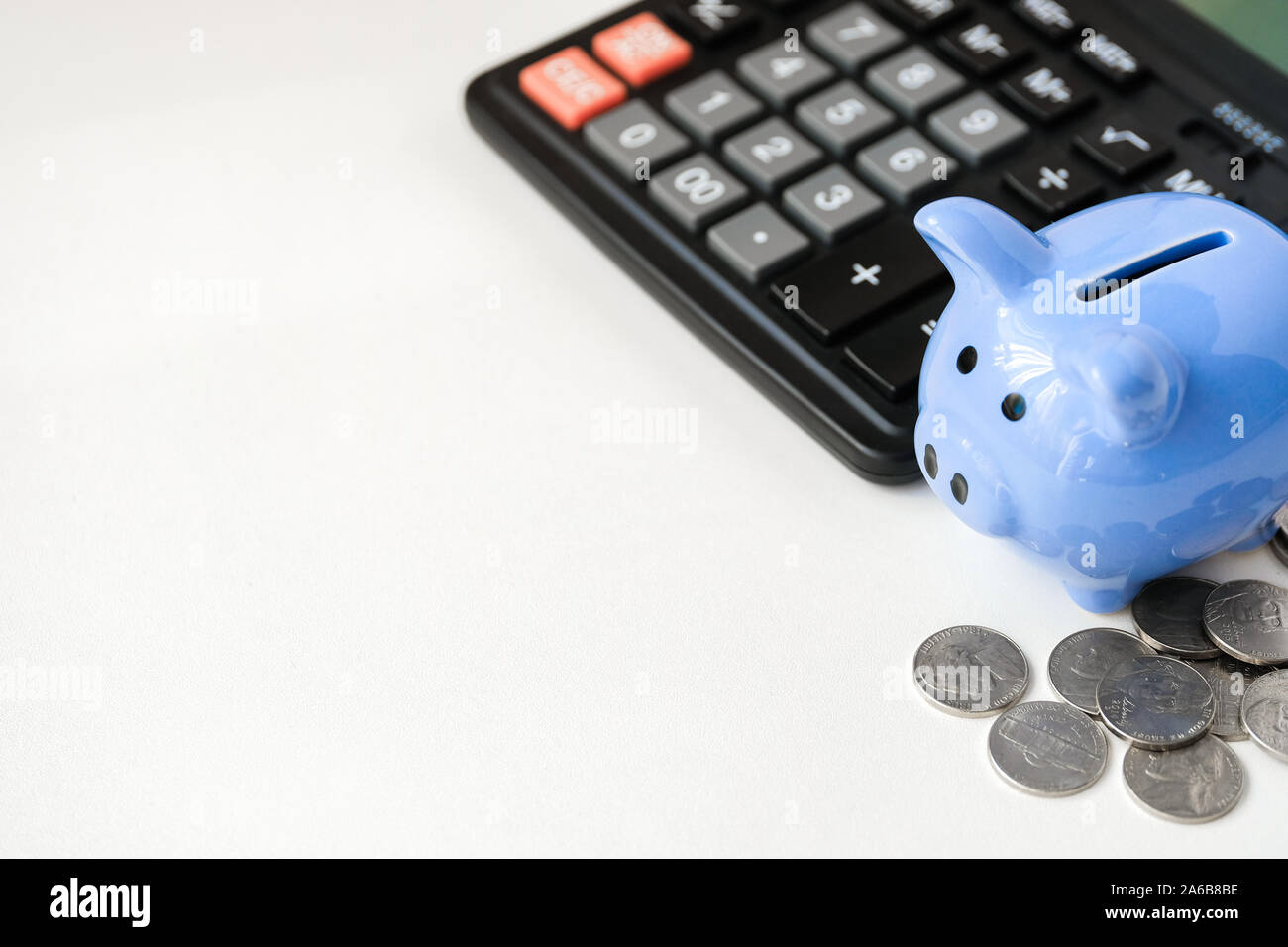 Blue piggy bank, calculator and coins on white background with copy ...