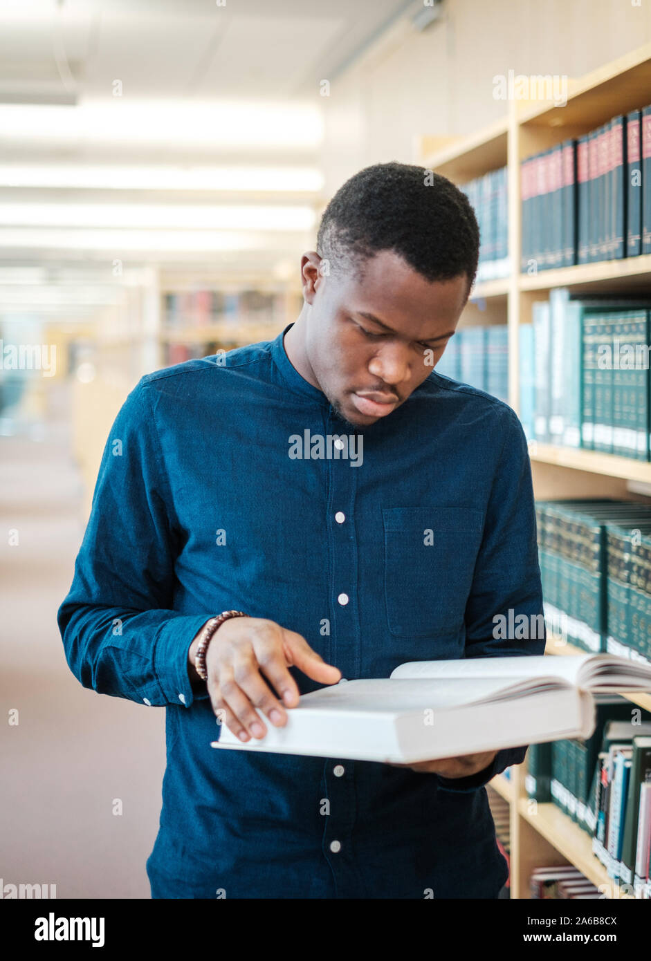 Young black man choosing book in public library Stock Photo - Alamy