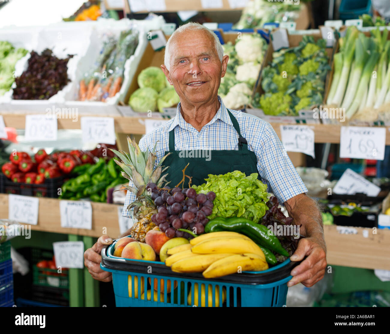 Portrait of friendly senior man owner of greengrocery shop with full ...