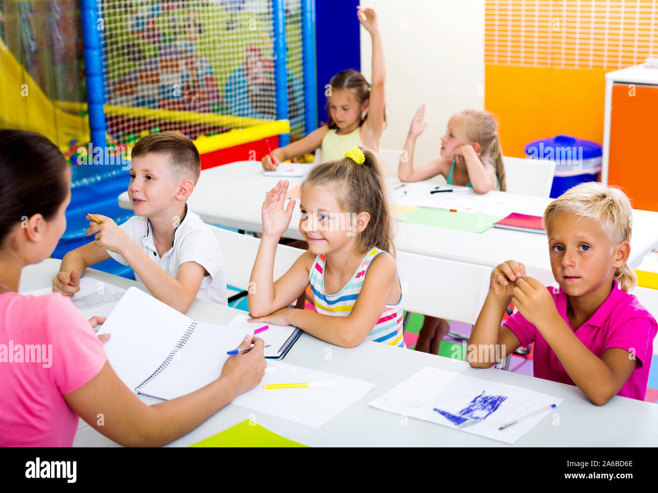 Attentive kids sitting and listening beautiful young teacher in ...