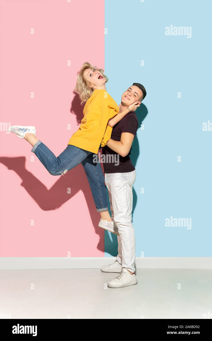 Young emotional man and woman in bright casual clothes posing on pink ...