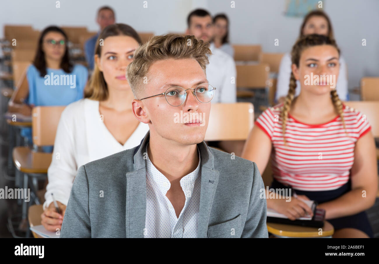 Portrait of young man in glasses attentively listening to lecture in ...