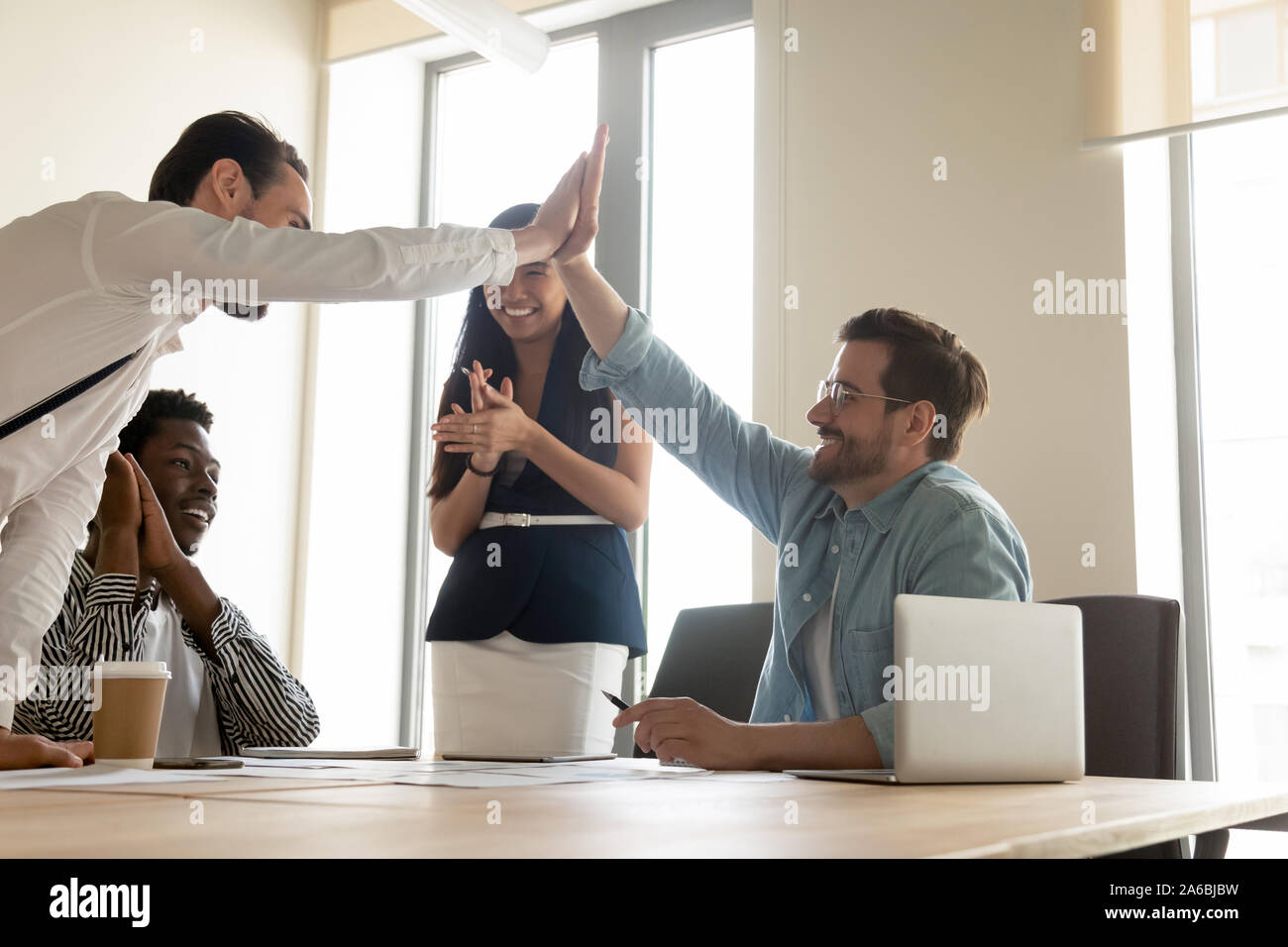 Happy colleagues giving high five at briefing, celebrating teamwork ...