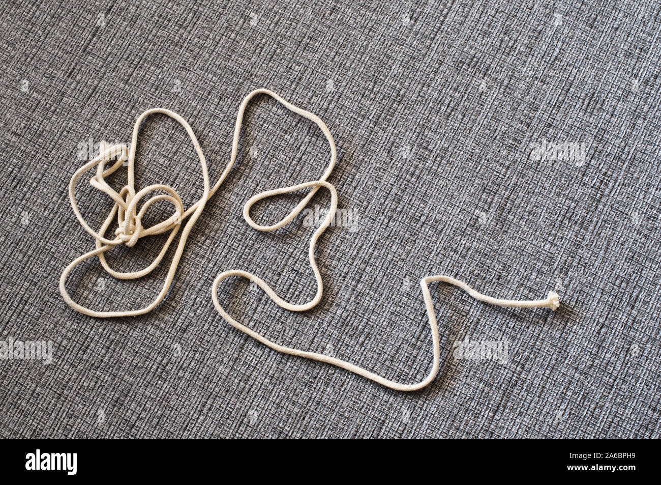 Tangled string on gray fabric Stock Photo - Alamy