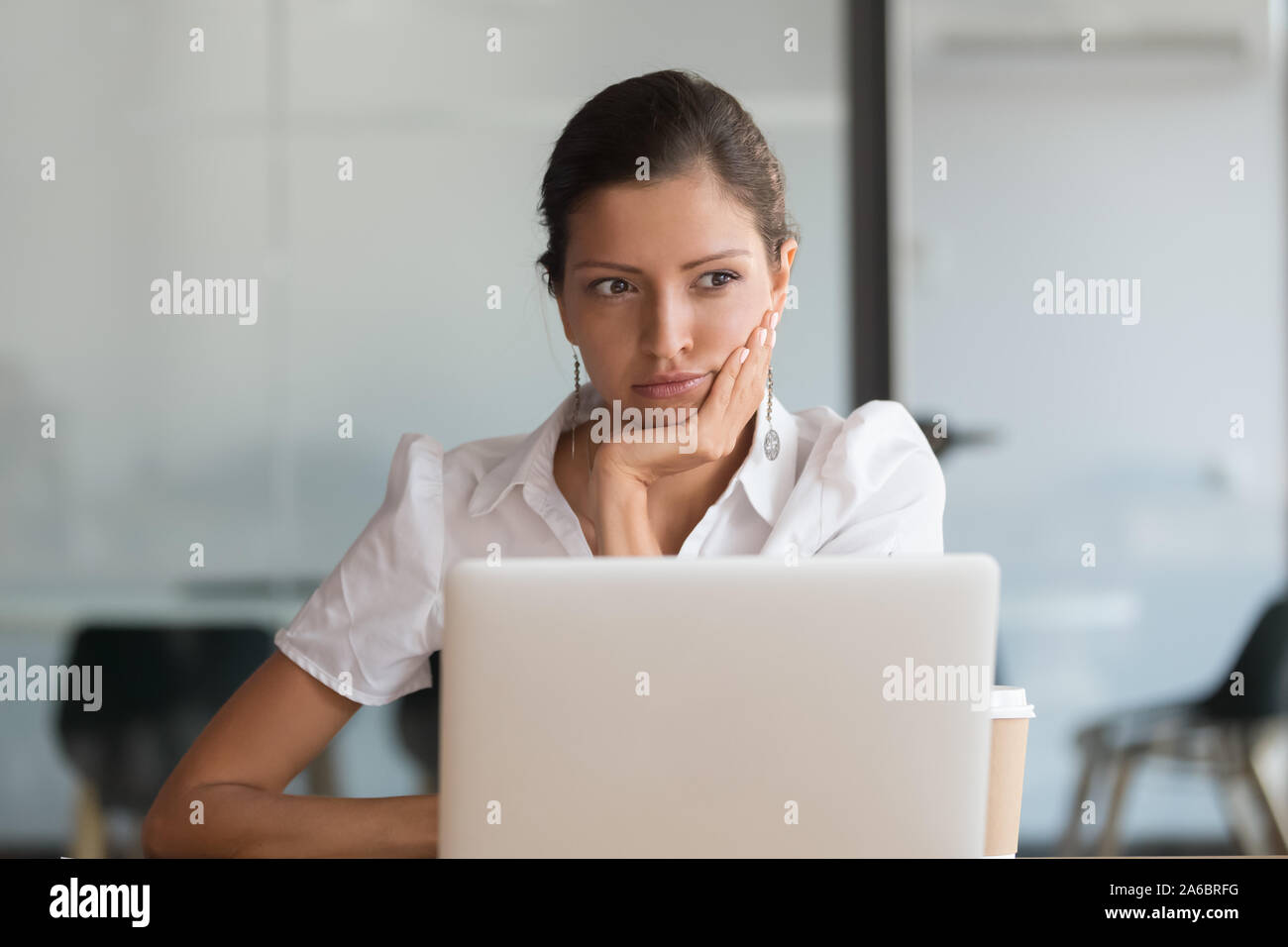 Unconcentrated young female employee feeling bored at working place ...