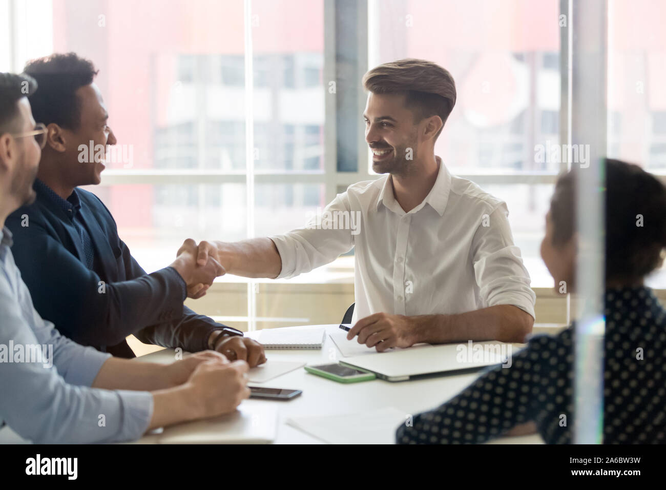 Young positive businessmen handshaking greeting each other Stock Photo ...