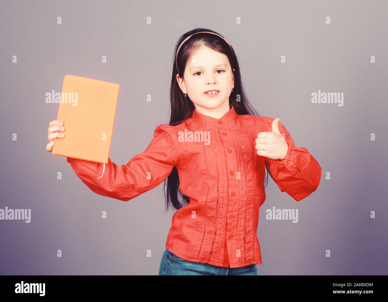 Gesturing thumbs up to reading. Adorable small child approving book for ...