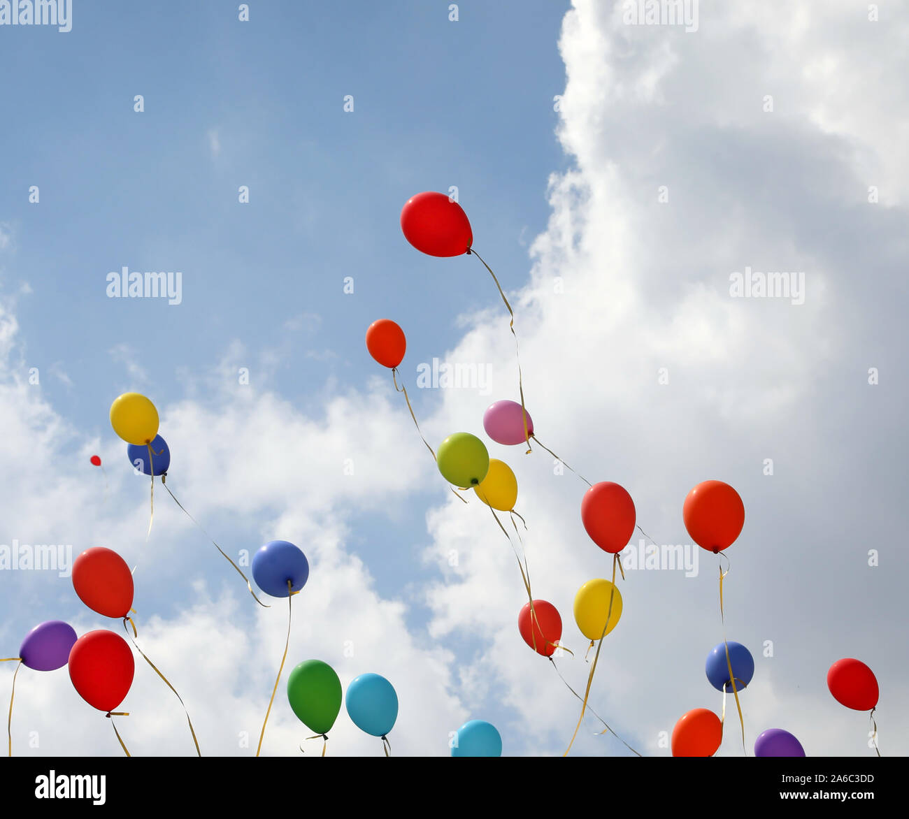 many colored balloons flying on the blue sky with clouds during a ...