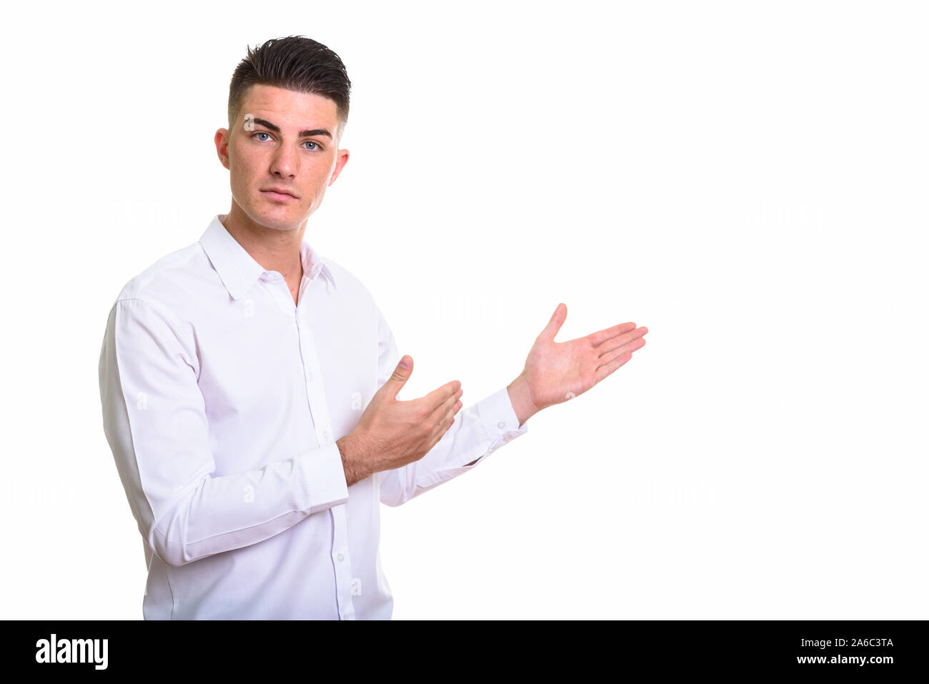 Studio shot of young handsome man showing something Stock Photo - Alamy