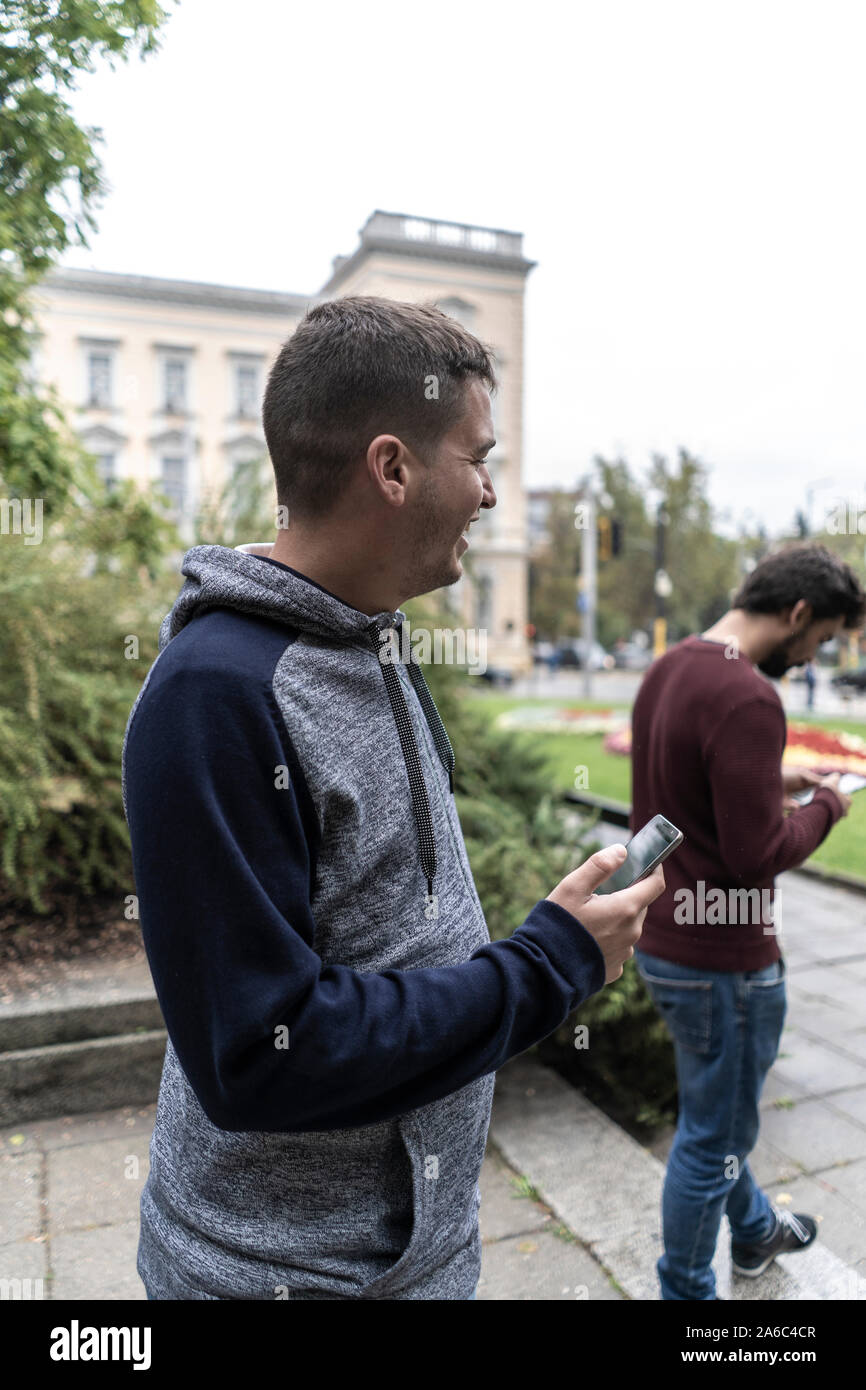 Young man using his mobile in the street Stock Photo - Alamy