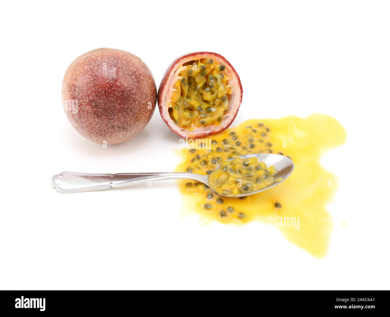 Whole passion fruit and half-eaten cross section with spoon and spilled ...