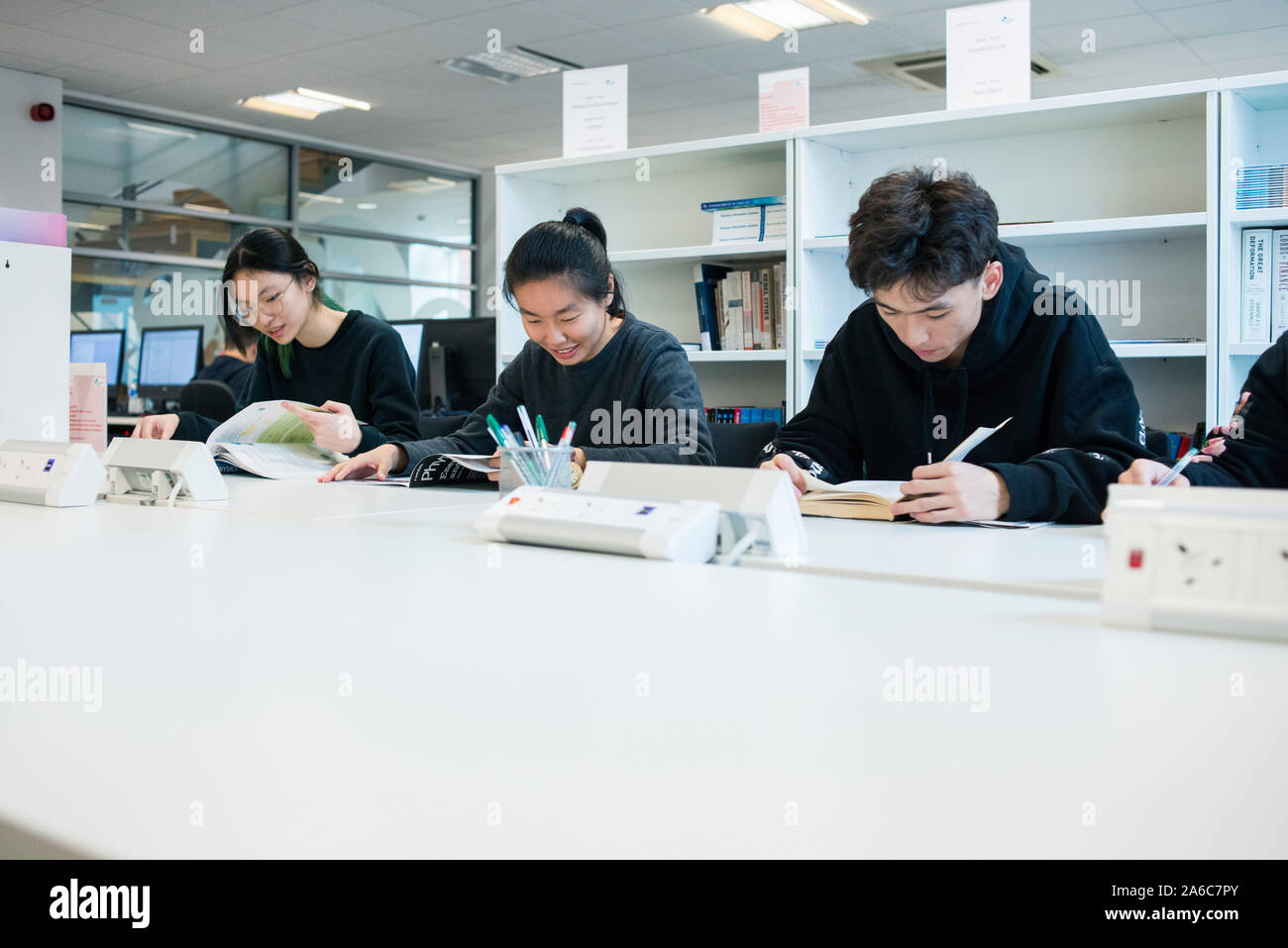 International overseas students sitting in a University library reading ...