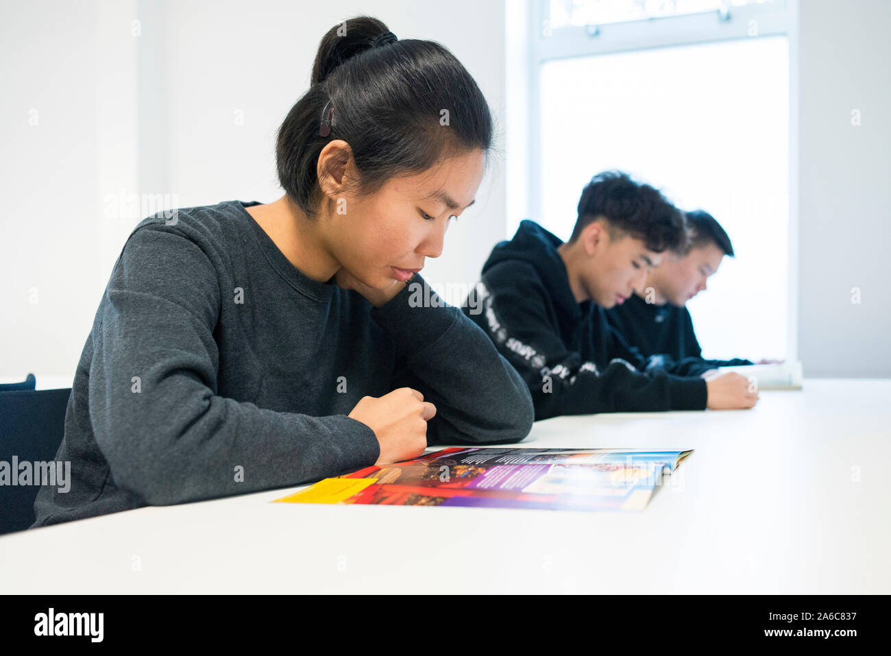 International overseas students sitting in a University library reading ...