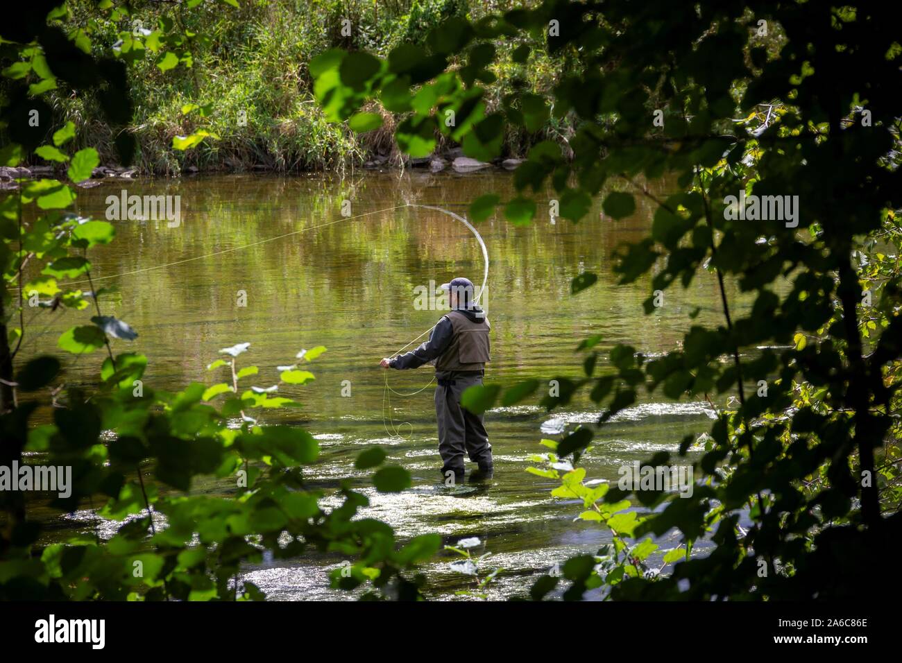 A portrait of a fisher man fishing in a river. The fisher man is ...
