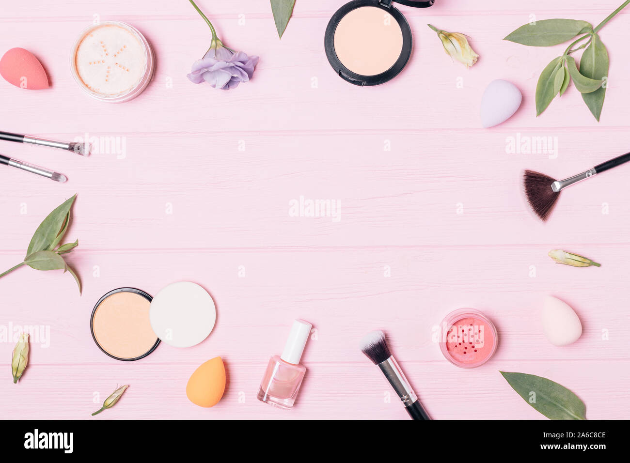 Flat lay frame of makeup products and accessories with fresh flowers on ...