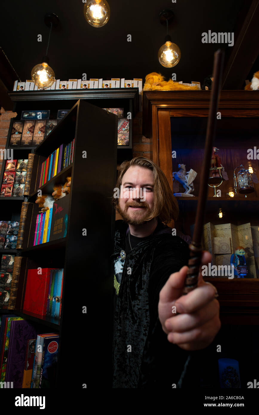 A wizard man appears from a secret opening book case holding a magic ...