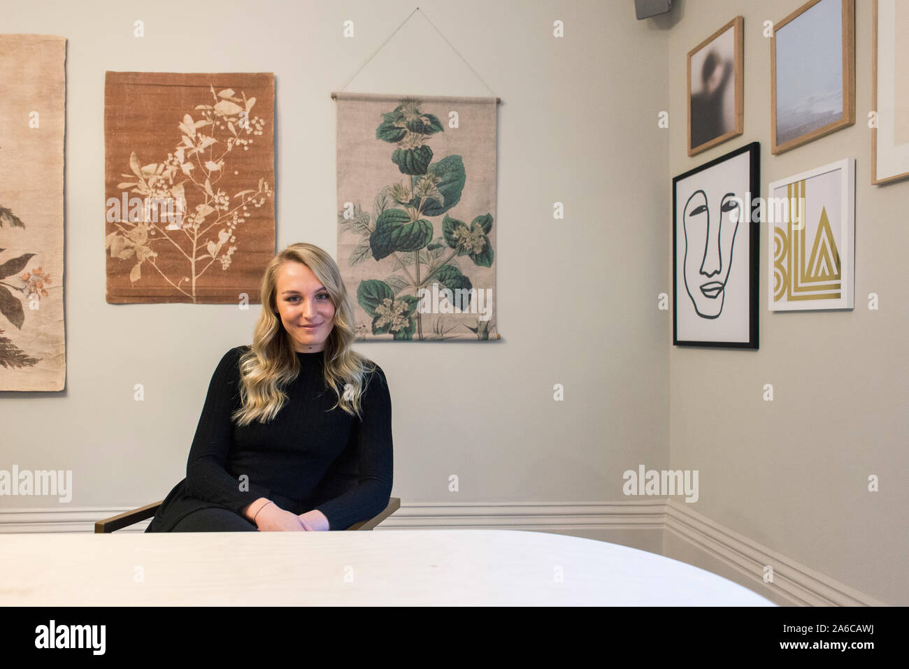 A female member of staff sits at a table in a cool meeting room and ...