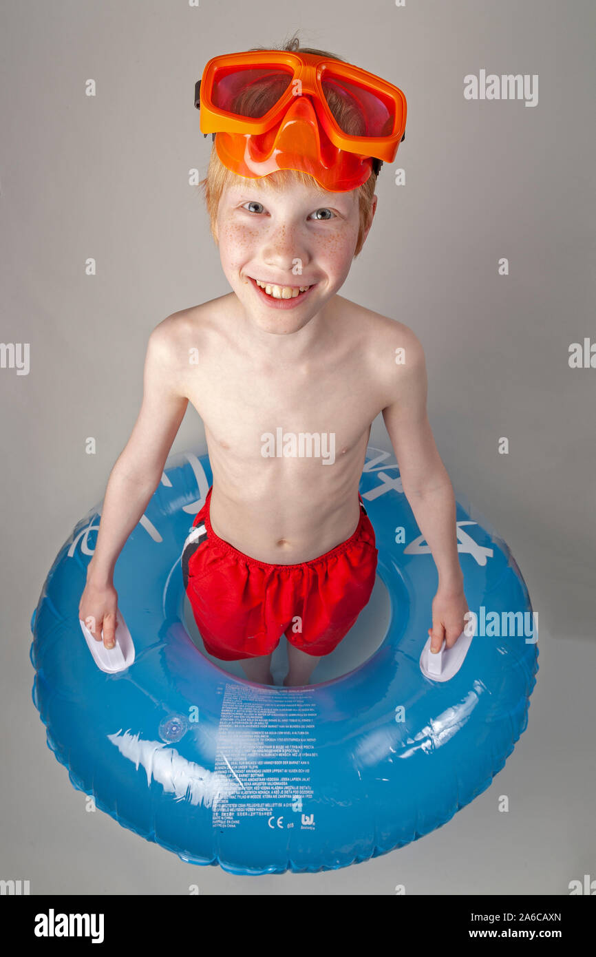 A young boy with diving goggles and floating tire is ready for the ...