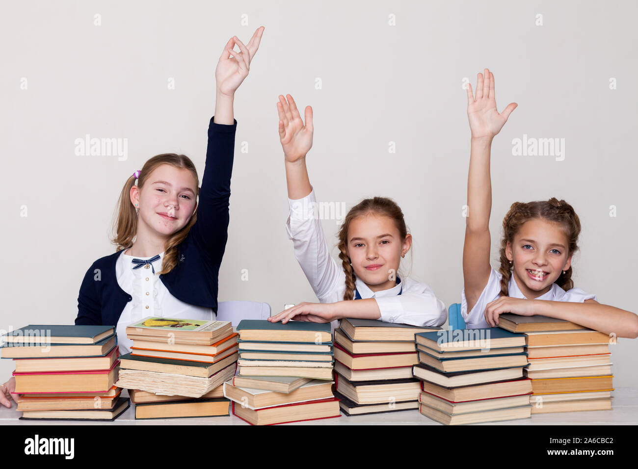 three girls raise their hand up in school class Stock Photo - Alamy