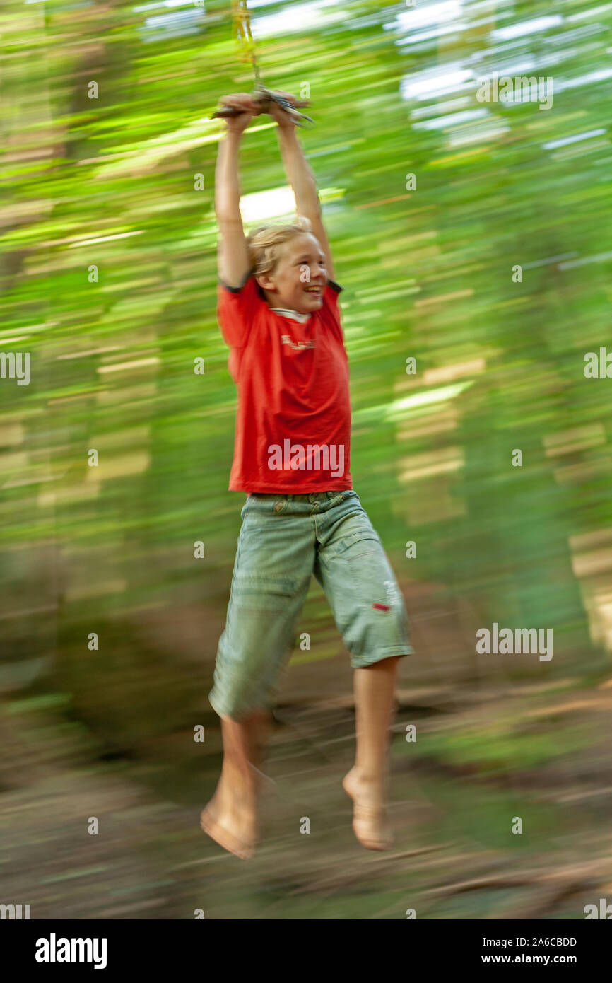 A boy is swinging on a rope in a forest Stock Photo - Alamy
