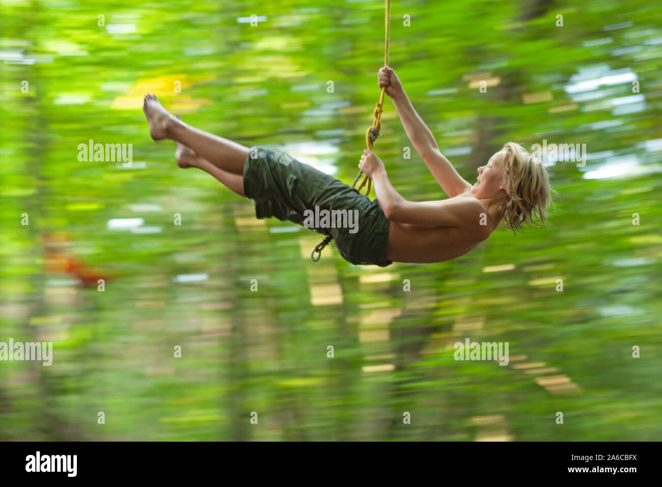 A boy is swinging on a rope in a forest Stock Photo - Alamy