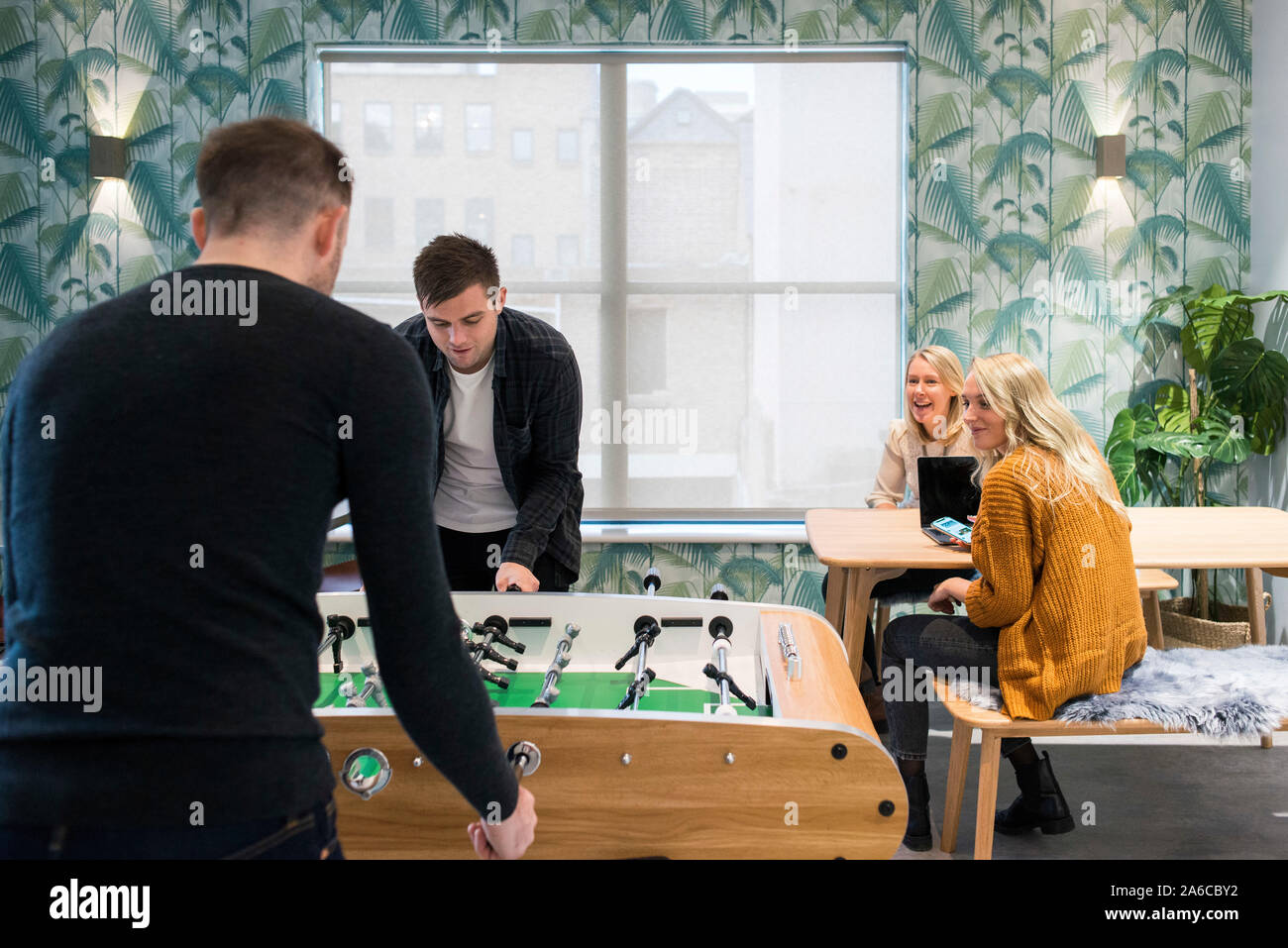 two men play table football in a staff room at a creative office space ...