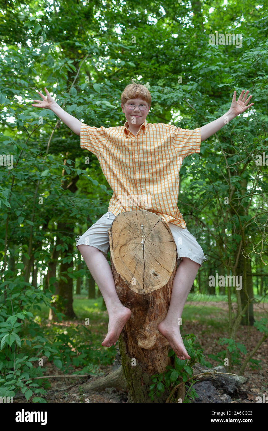 A young boy sitting on a tree trunk Stock Photo - Alamy