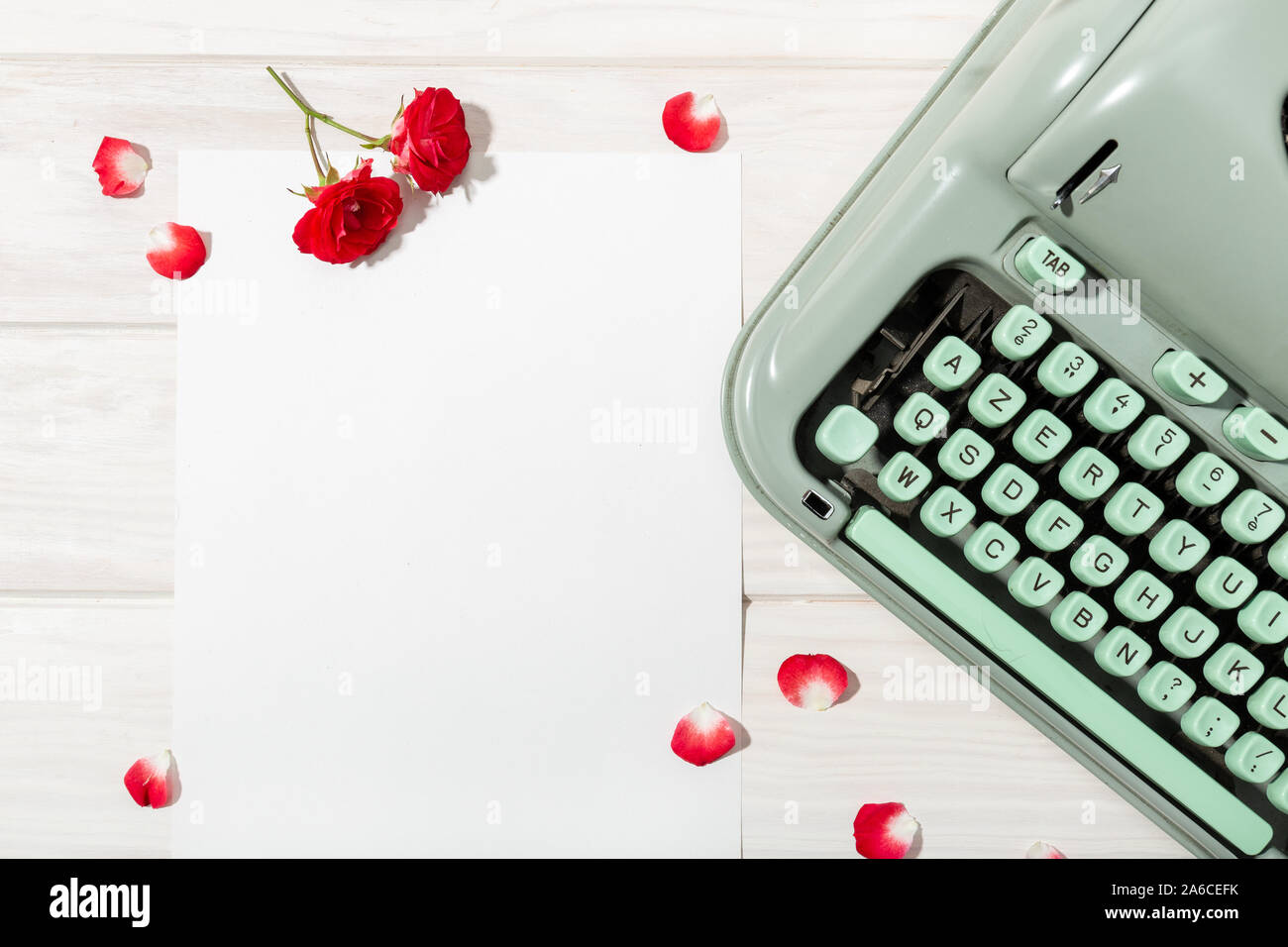 Love letter. Desk with blank paper, retro typewriter and red roses and ...
